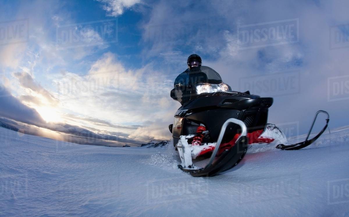 Man driving snowmobile in snowy field - Royalty-free Stock Photo | Dissolve