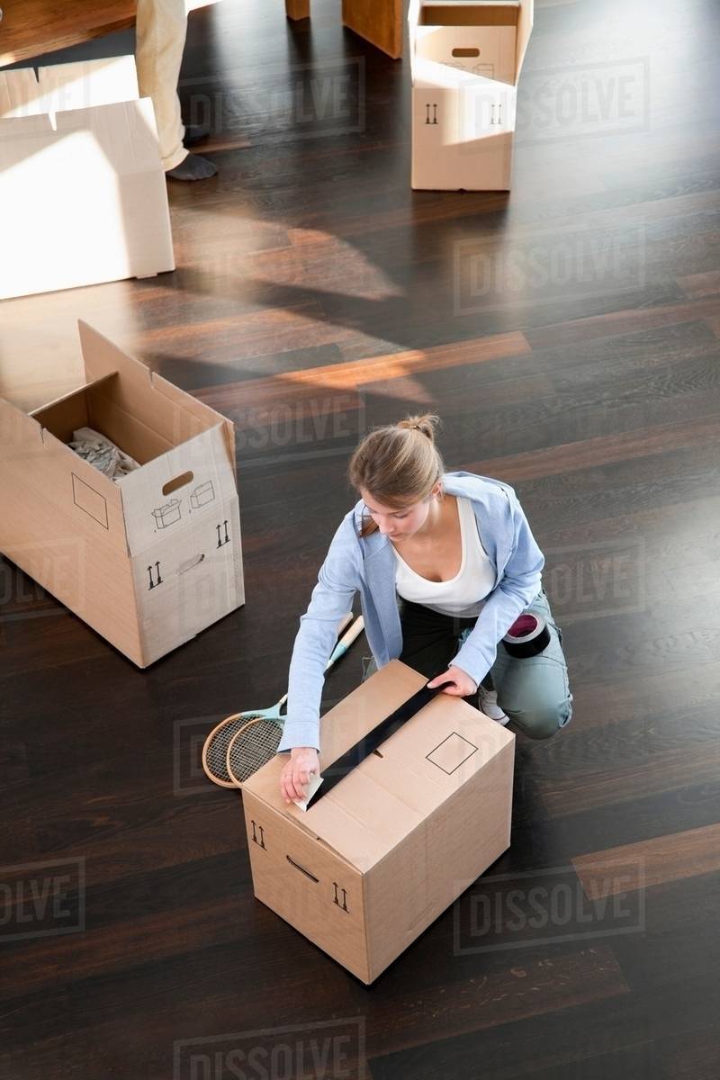 Woman taping up cardboard box - Stock Photo - Dissolve
