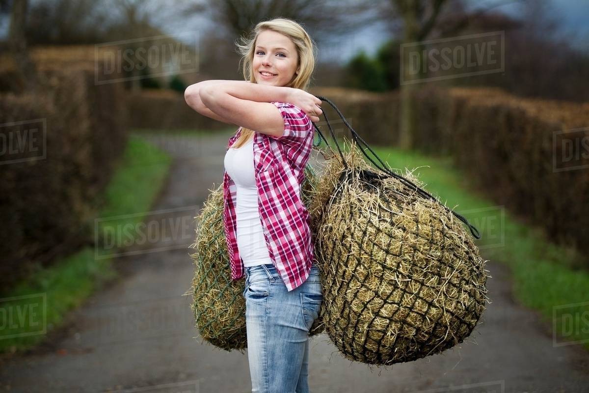 Teenage girl carrying hay on dirt path - Royalty-free Stock Photo ...