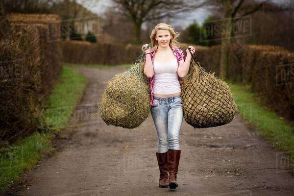 Teenage girl carrying hay on dirt path - Royalty-free Stock Photo ...