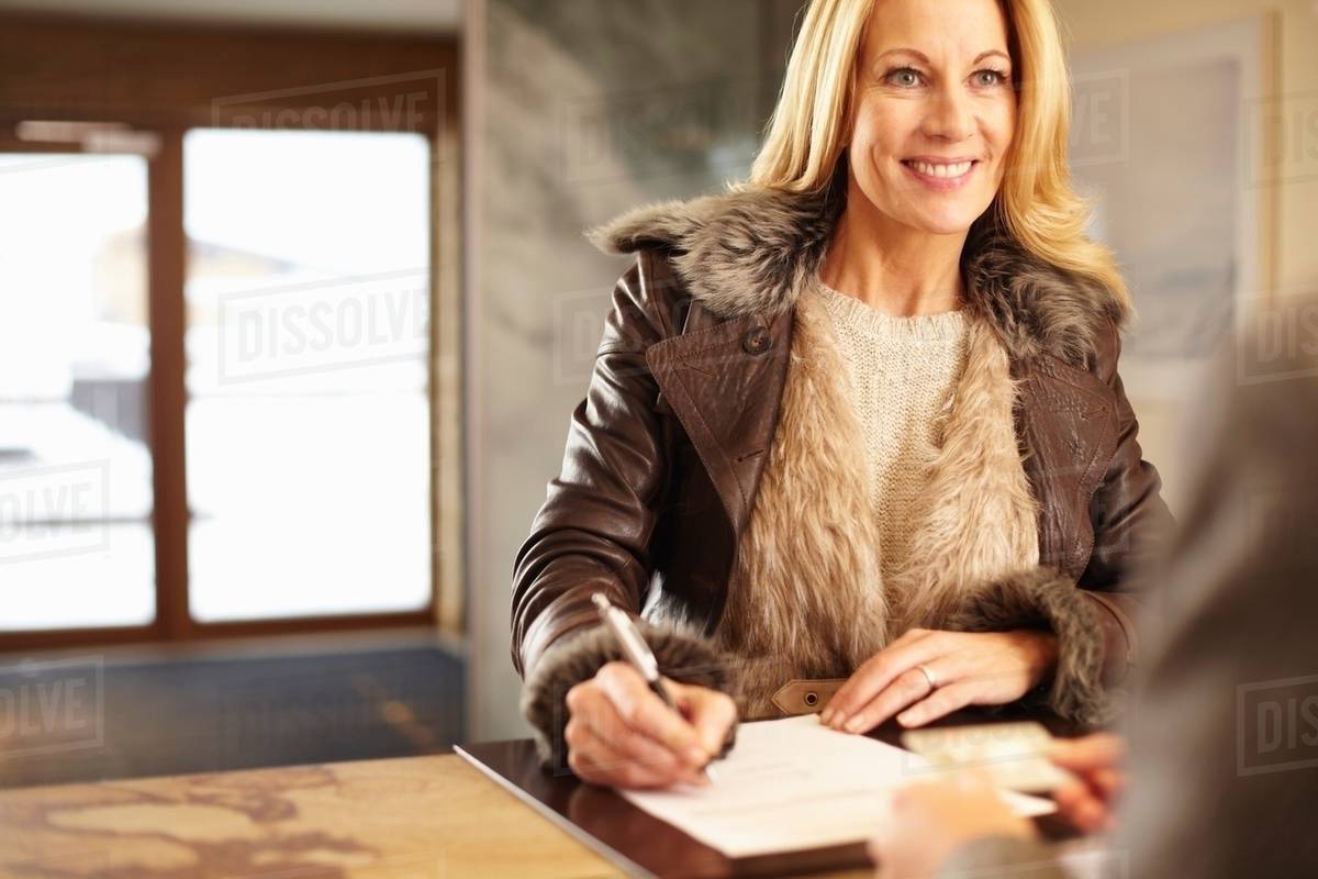 Woman checking in to hotel - Stock Photo - Dissolve