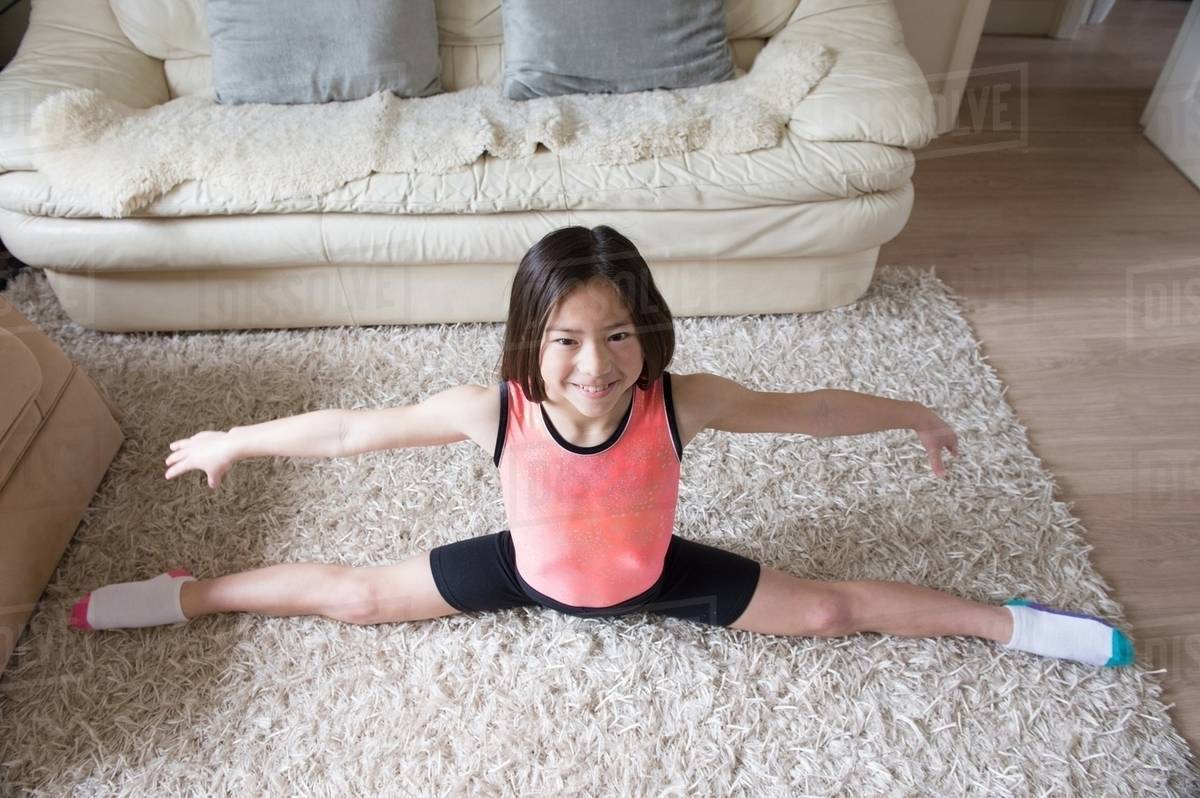 Girl practicing gymnastic splits on living room rug - Stock Photo ...
