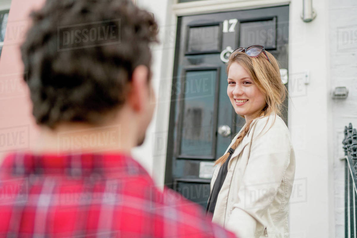 Young woman and boyfriend at front door, Kings Road, London, UK ...