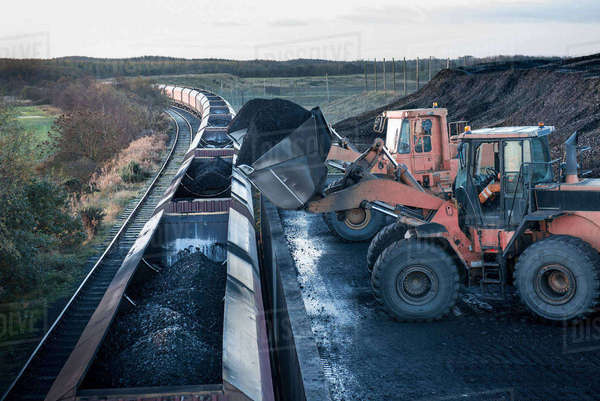 Diggers loading coal onto train at surface coal mine at dawn - Stock ...