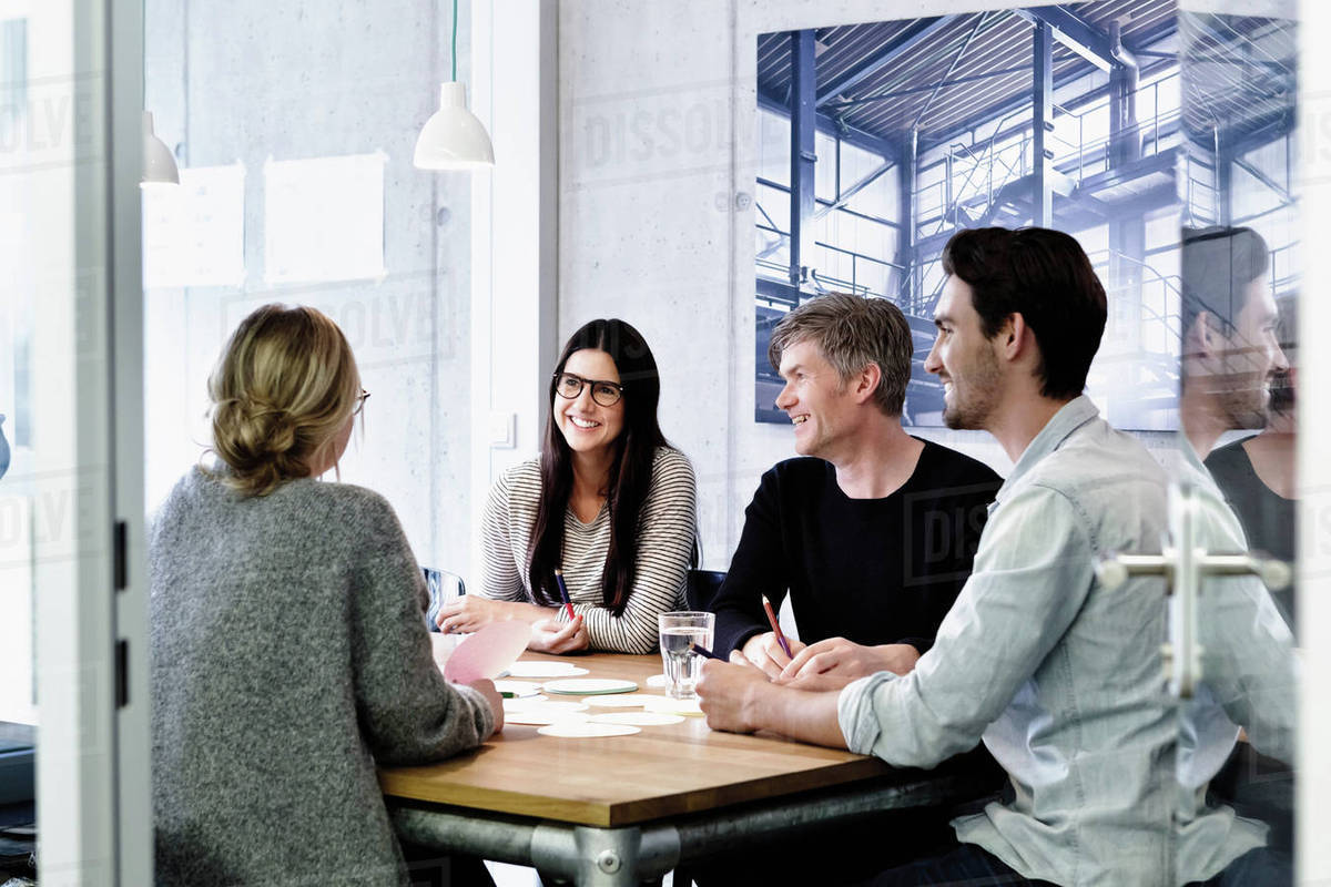 Colleagues at meeting in conference room smiling - Stock Photo - Dissolve