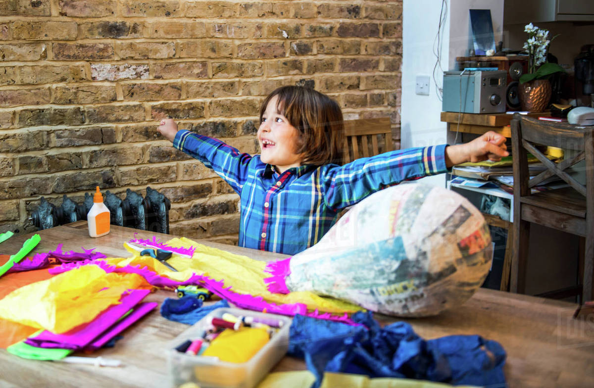 Boy decorating pinata at home - Stock Photo - Dissolve