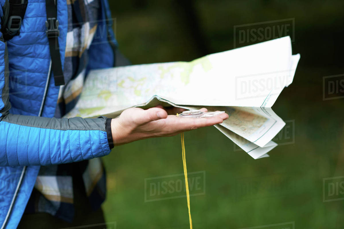 Cropped view of hiker looking at paper map and compass - Royalty-free ...