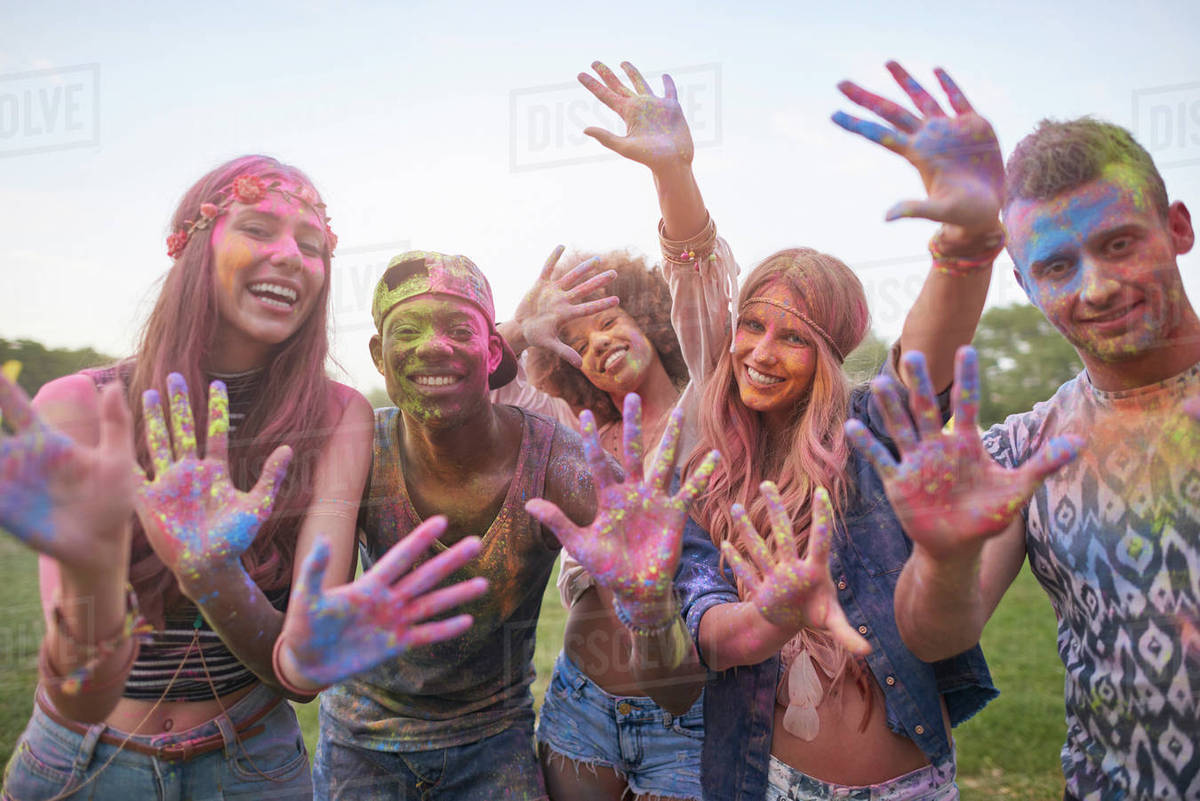 Portrait of group of friends at festival, covered in colourful powder ...