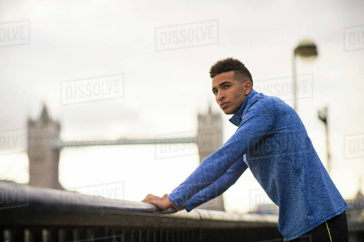 Man standing by riverside, Tower Bridge in background, Wapping, London ...