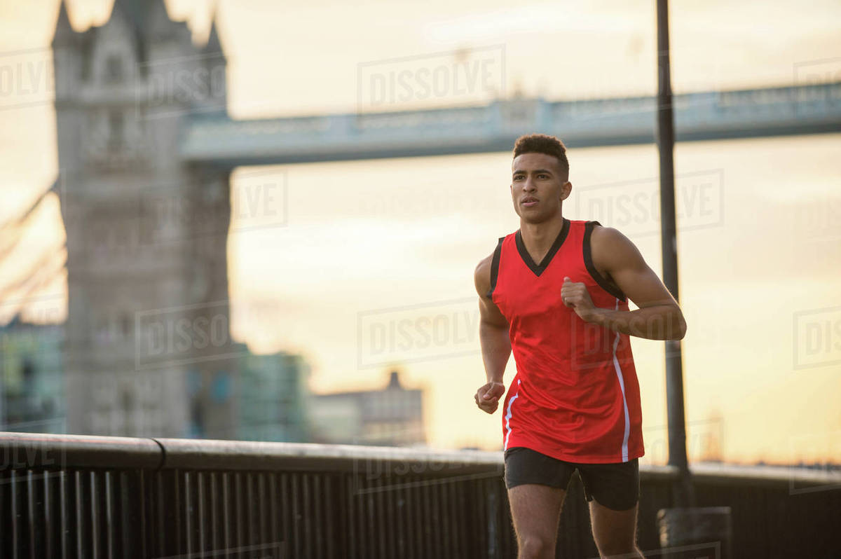 Man running by riverside, Tower Bridge in background, Wapping, London ...