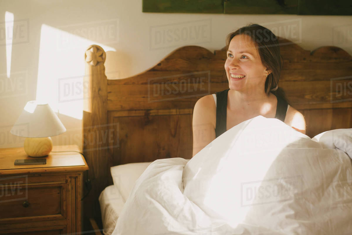 Woman smiling in bed - Royalty-free Stock Photo | Dissolve