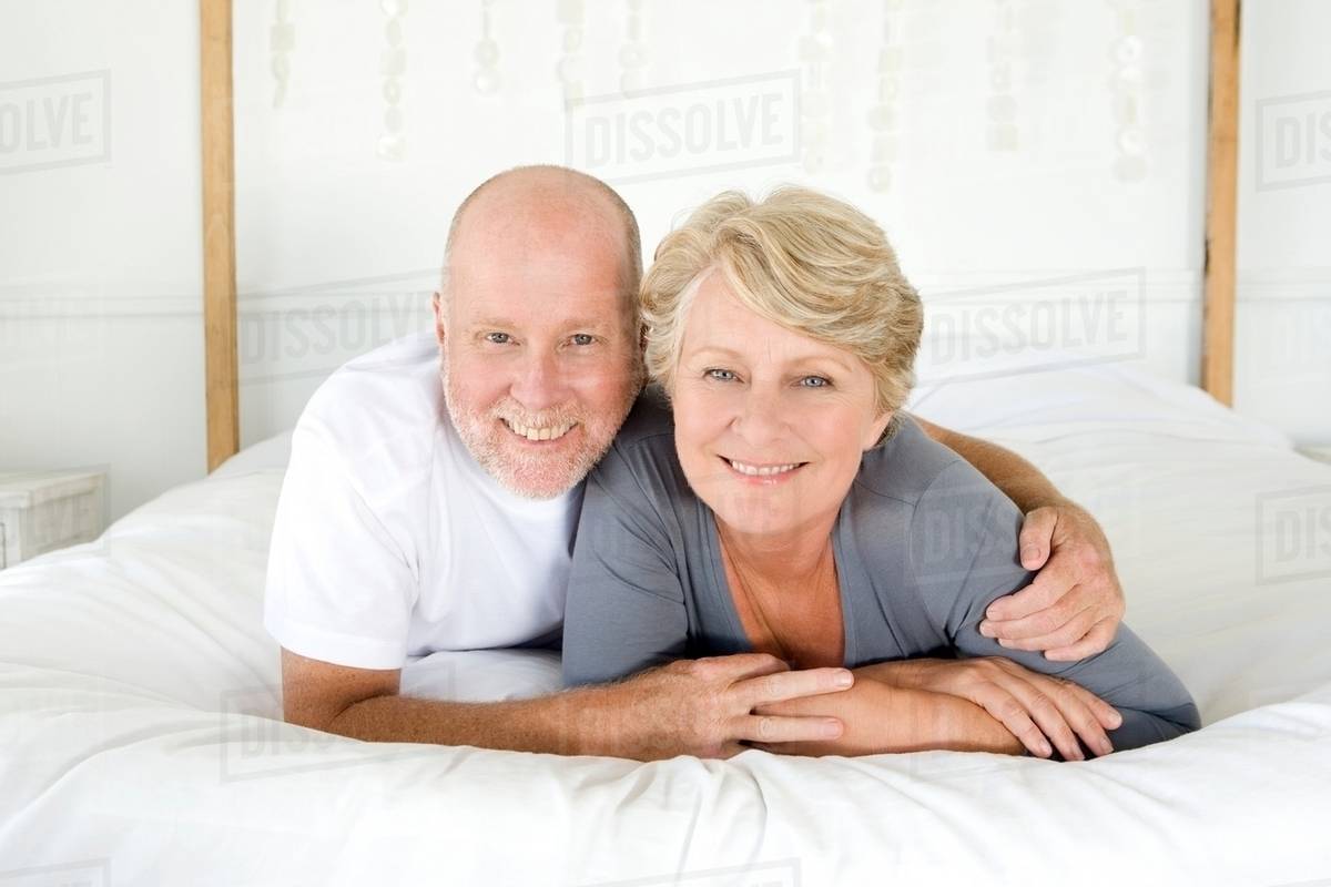 Smiling older couple laying on bed - Royalty-free Stock Photo | Dissolve