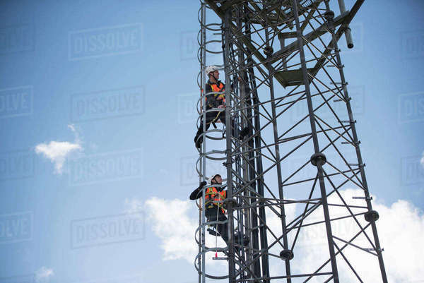 Engineers climbing transmission tower, low angle view - Stock Photo ...