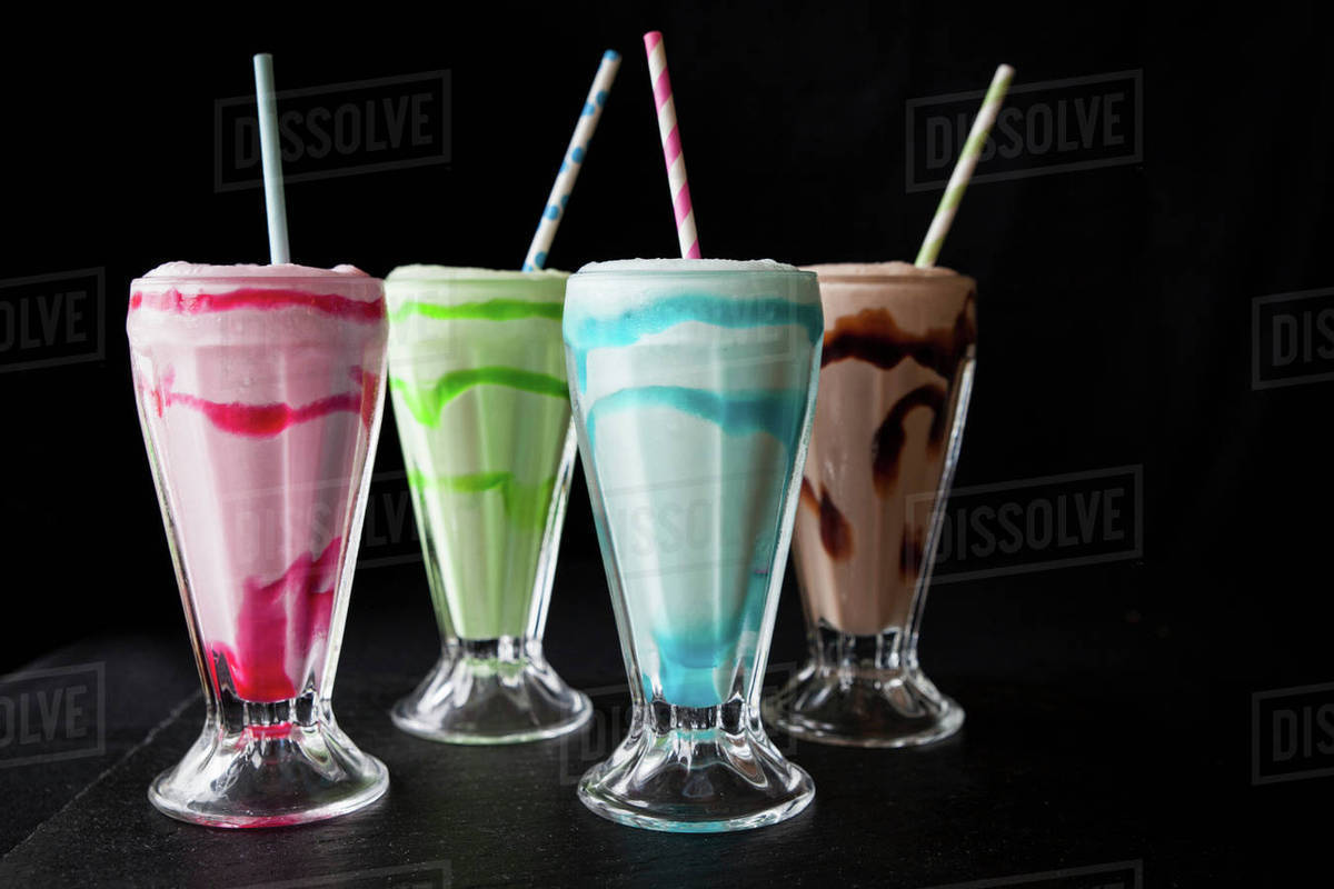 Four colourful milkshakes with drinking straws on table - Royalty-free ...