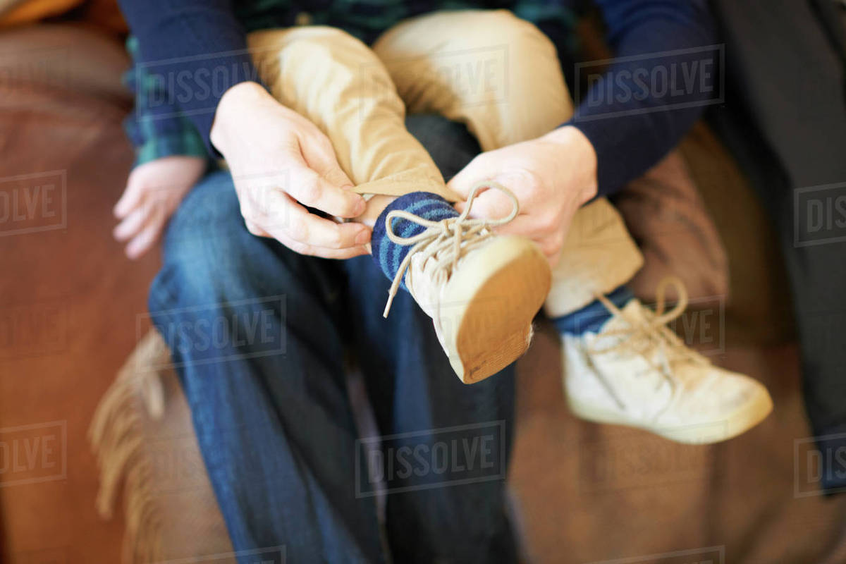 Adult helping child with shoes - Stock Photo - Dissolve