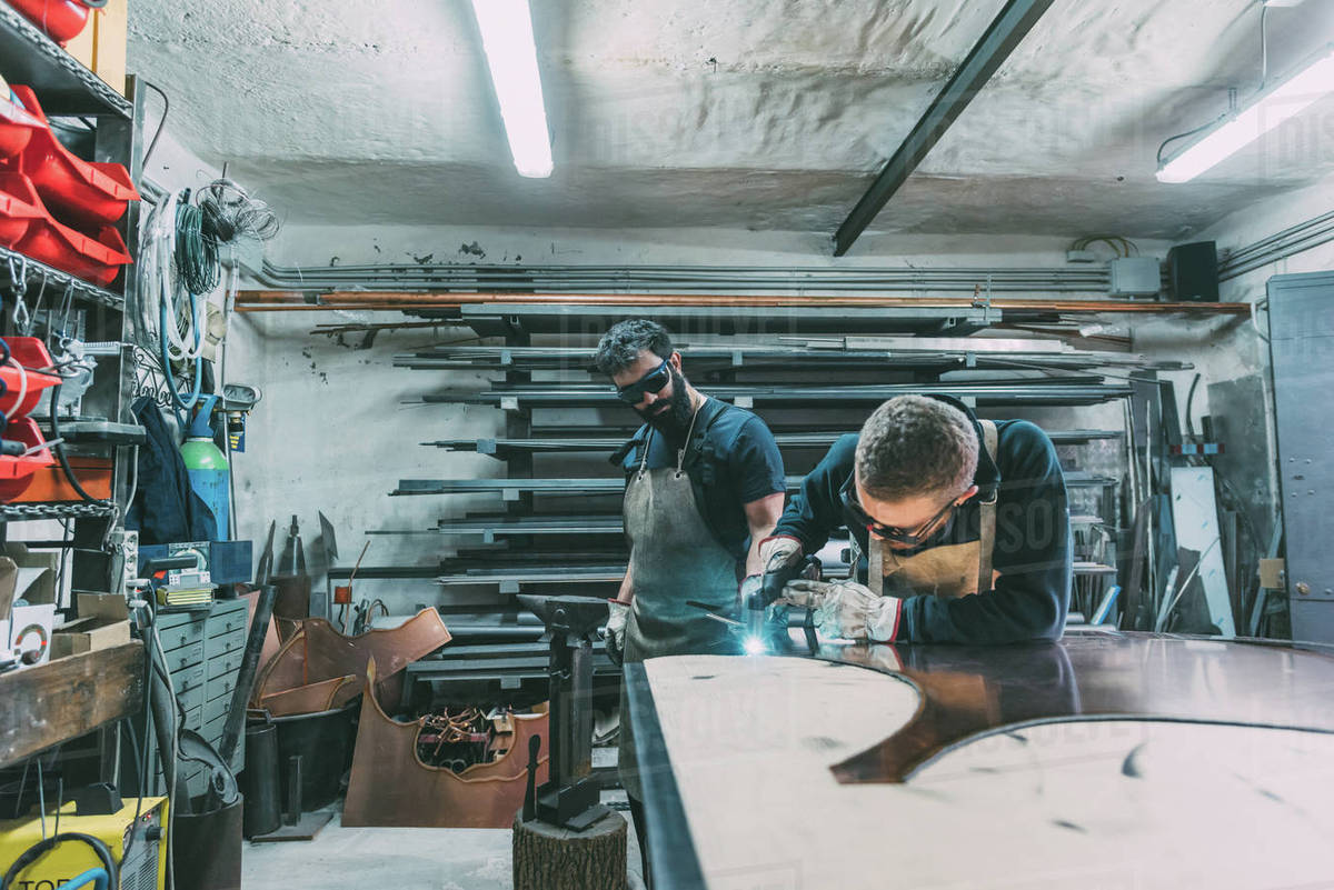 Metalworker cutting copper with welding torch in forge workshop ...