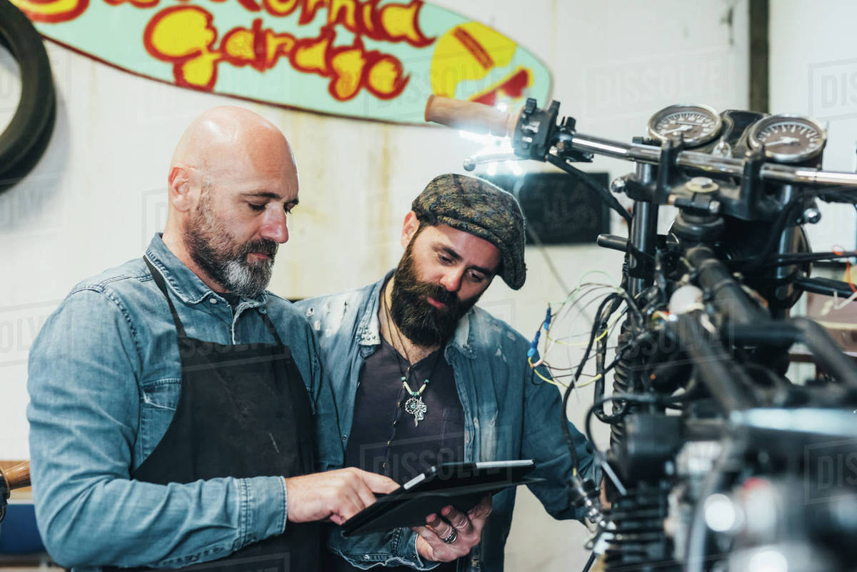 Two mature men, working in garage, using digital tablet - Stock Photo ...