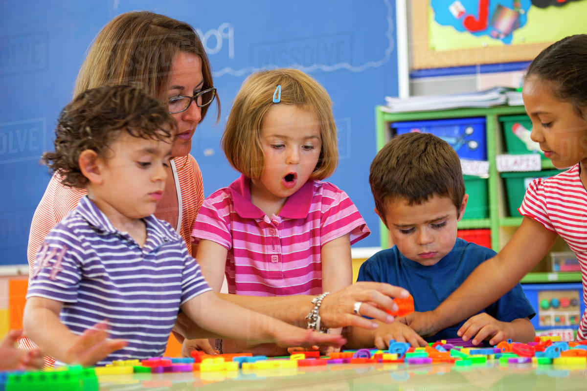 Female teacher with preschool boys and girls learning alphabet in ...