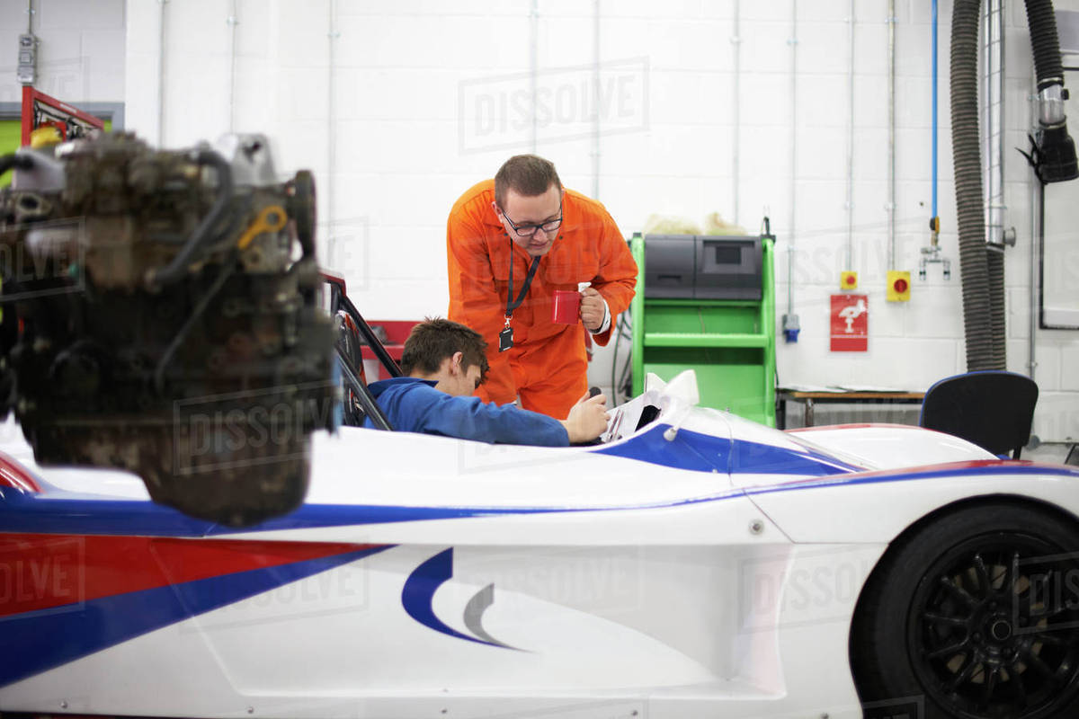 College mechanic students checking racing car in repair garage ...