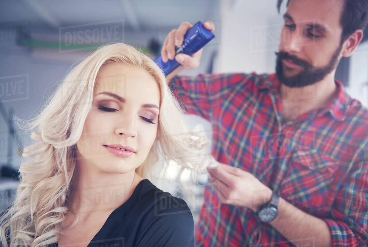 Male hairdresser putting hairspray on model for photo shoot - Stock ...
