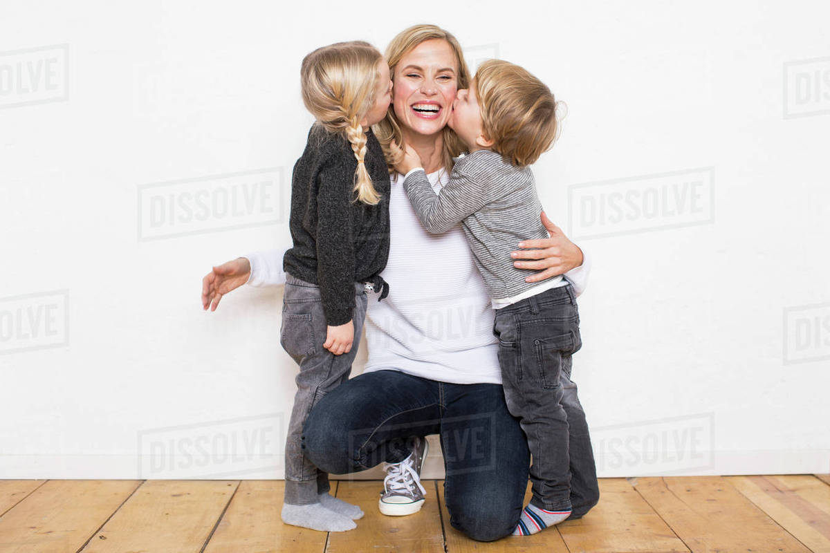 Portrait of mother, crouching, hugging son and daughter - Stock Photo ...