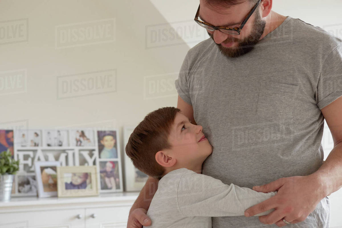 Boy hugging father in living room - Stock Photo - Dissolve