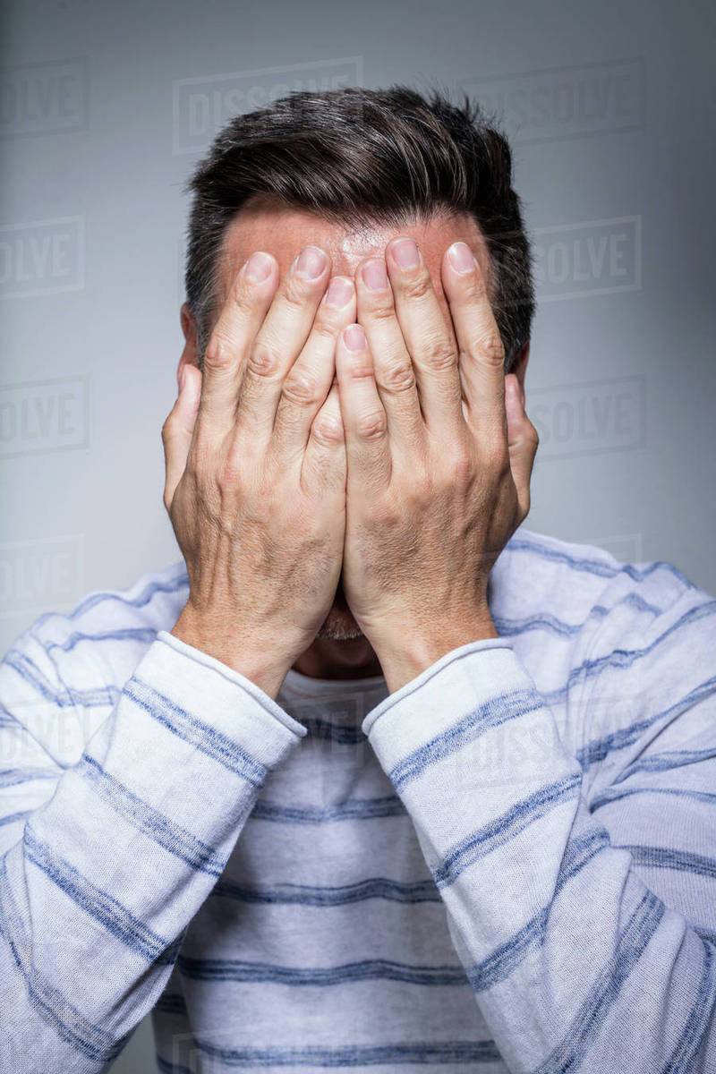 Studio shot of mature man with hands covering face - Stock Photo - Dissolve