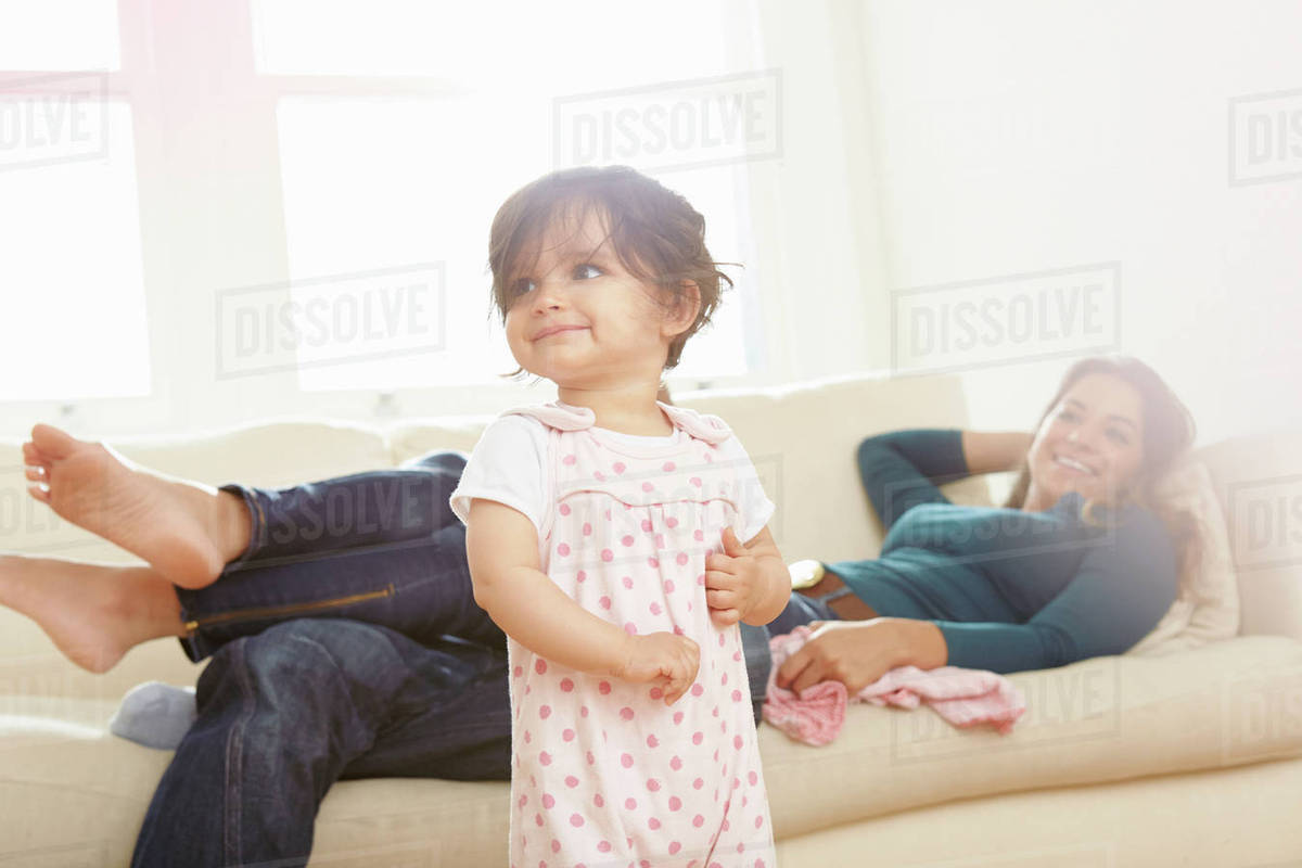 Baby girl toddling in living room with parents watching - Royalty-free ...