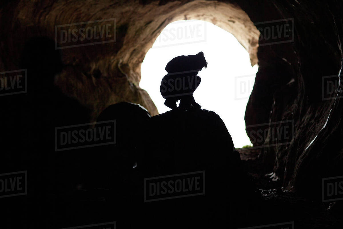 Silhouette of woman crouching on rock in cave, Bruniquel, France ...