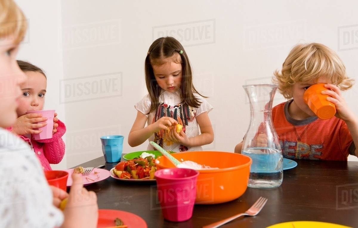 Children eating together at table - Stock Photo - Dissolve