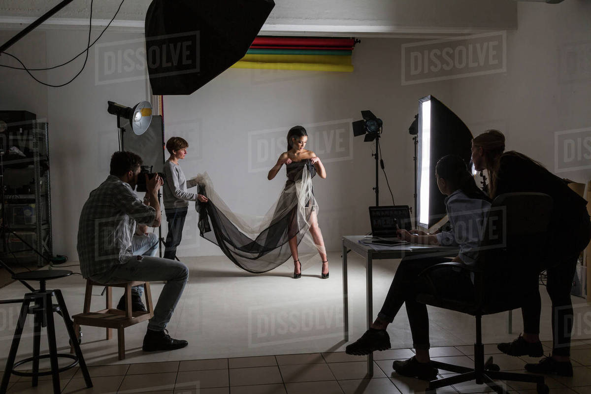 Photography team and model in low key photography studio shoot - Stock ...