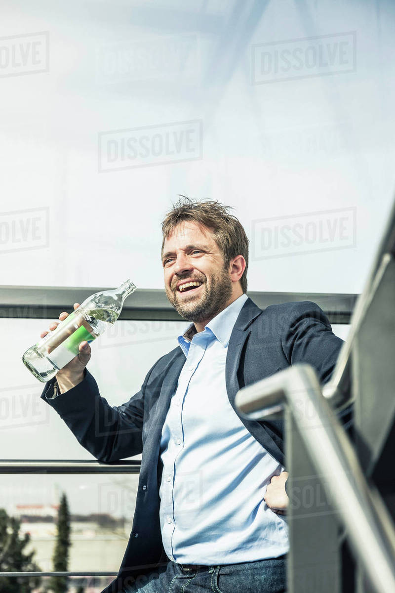 Businessman drinking bottled water on office stairway - Royalty-free ...