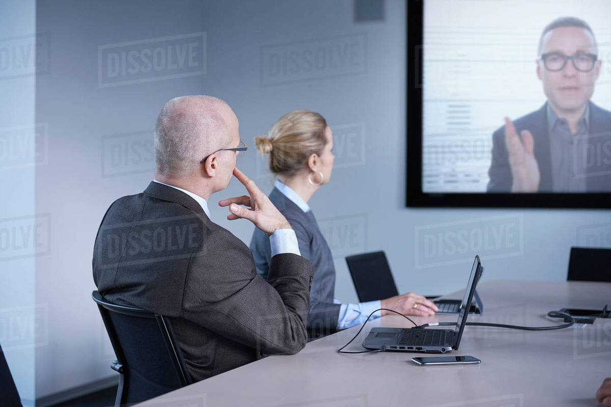 Businessman and woman watching office conference call - Royalty-free ...