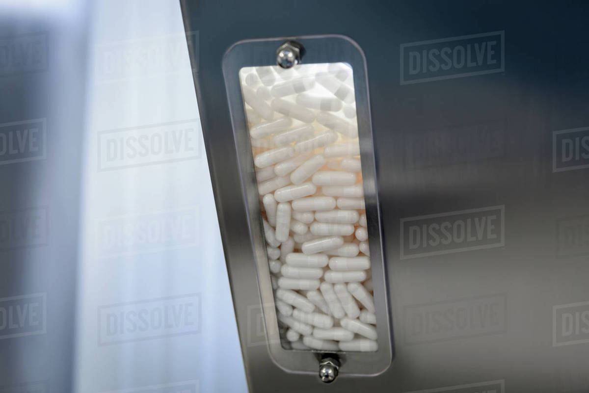 Capsules in hopper in pharmaceutical factory - Stock Photo - Dissolve