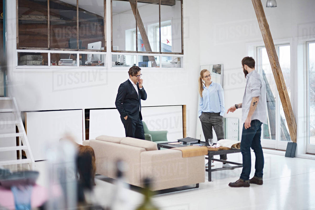 Interior design team pointing at wall paper roll in design studio ...