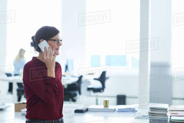 Woman in office making telephone call using mobile phone - Stock Photo ...