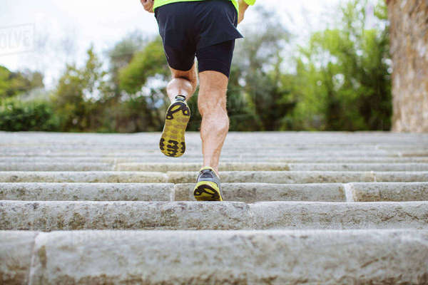 Rear view of senior man running up steps - Stock Photo - Dissolve