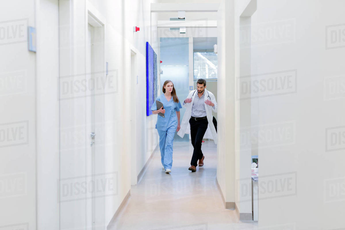 Doctors walking through hospital corridor - Stock Photo - Dissolve
