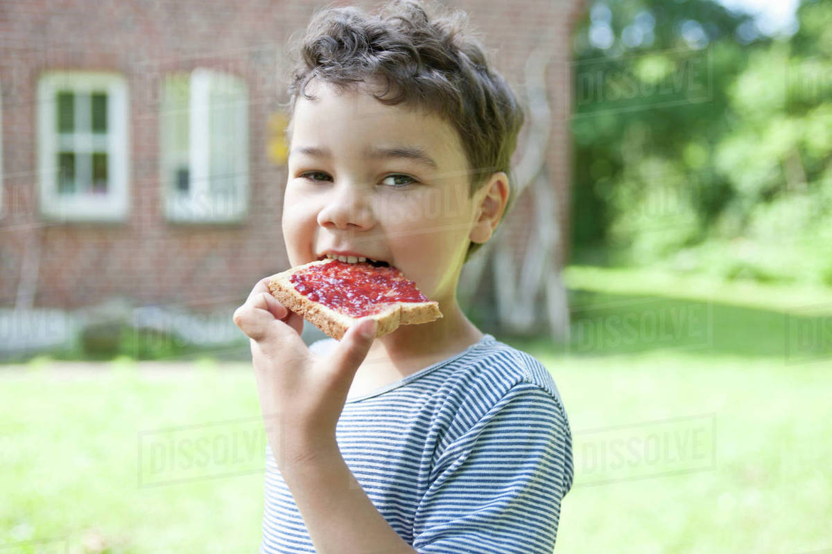 Boy eating bread with jam outdoors - Royalty-free Stock Photo | Dissolve