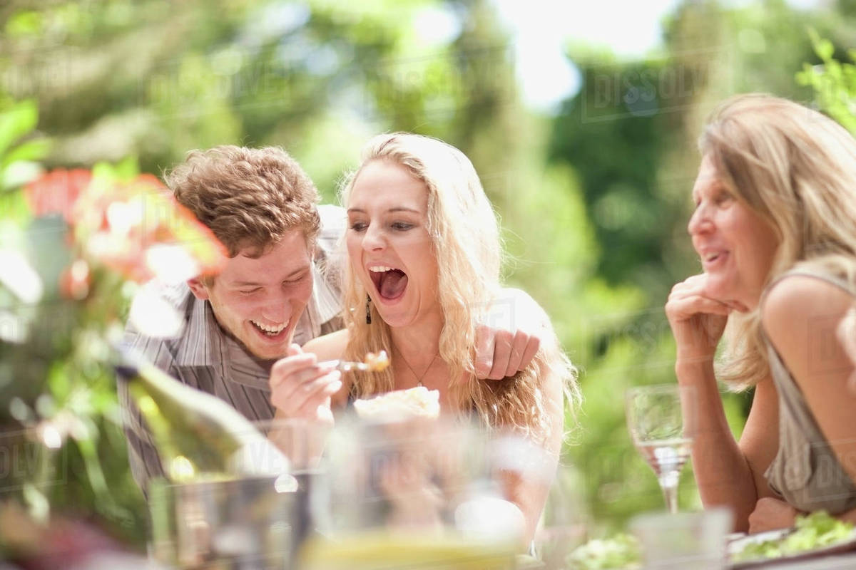 Family laughing at table outdoors - Stock Photo - Dissolve