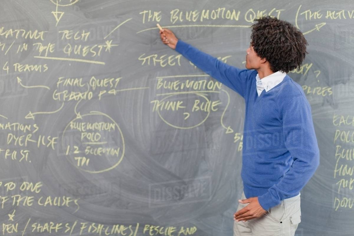 Teacher pointing to chalkboard - Royalty-free Stock Photo | Dissolve