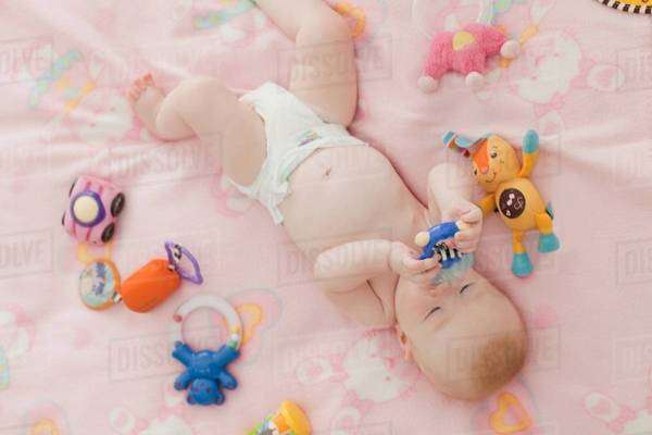 Baby chewing on rattle on blanket - Royalty-free Stock Photo | Dissolve