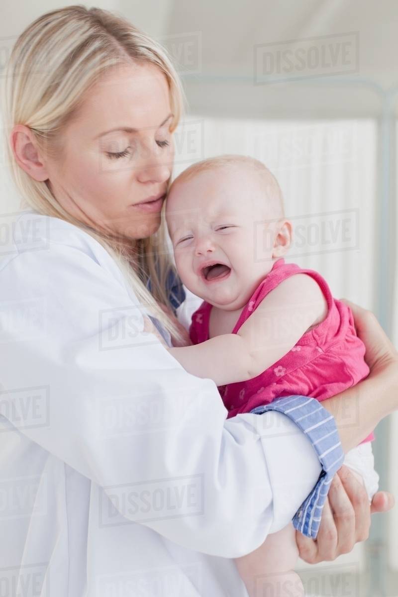 Doctor hugging crying baby - Royalty-free Stock Photo | Dissolve