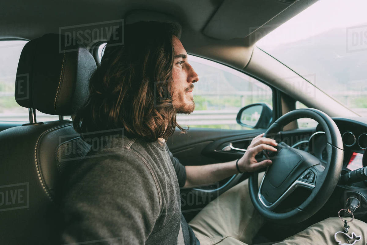 Young man driving car on rural road - Stock Photo - Dissolve