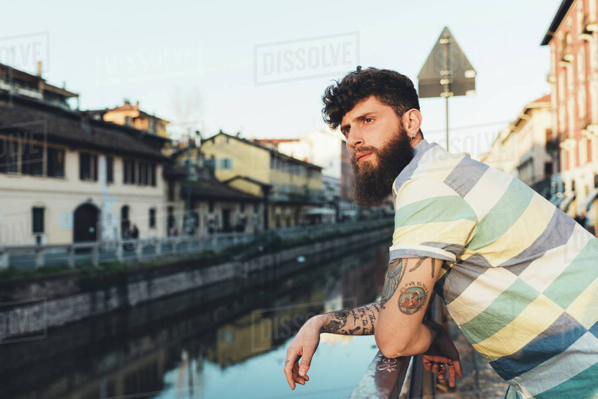 Man leaning against railing by canal - Royalty-free Stock Photo | Dissolve