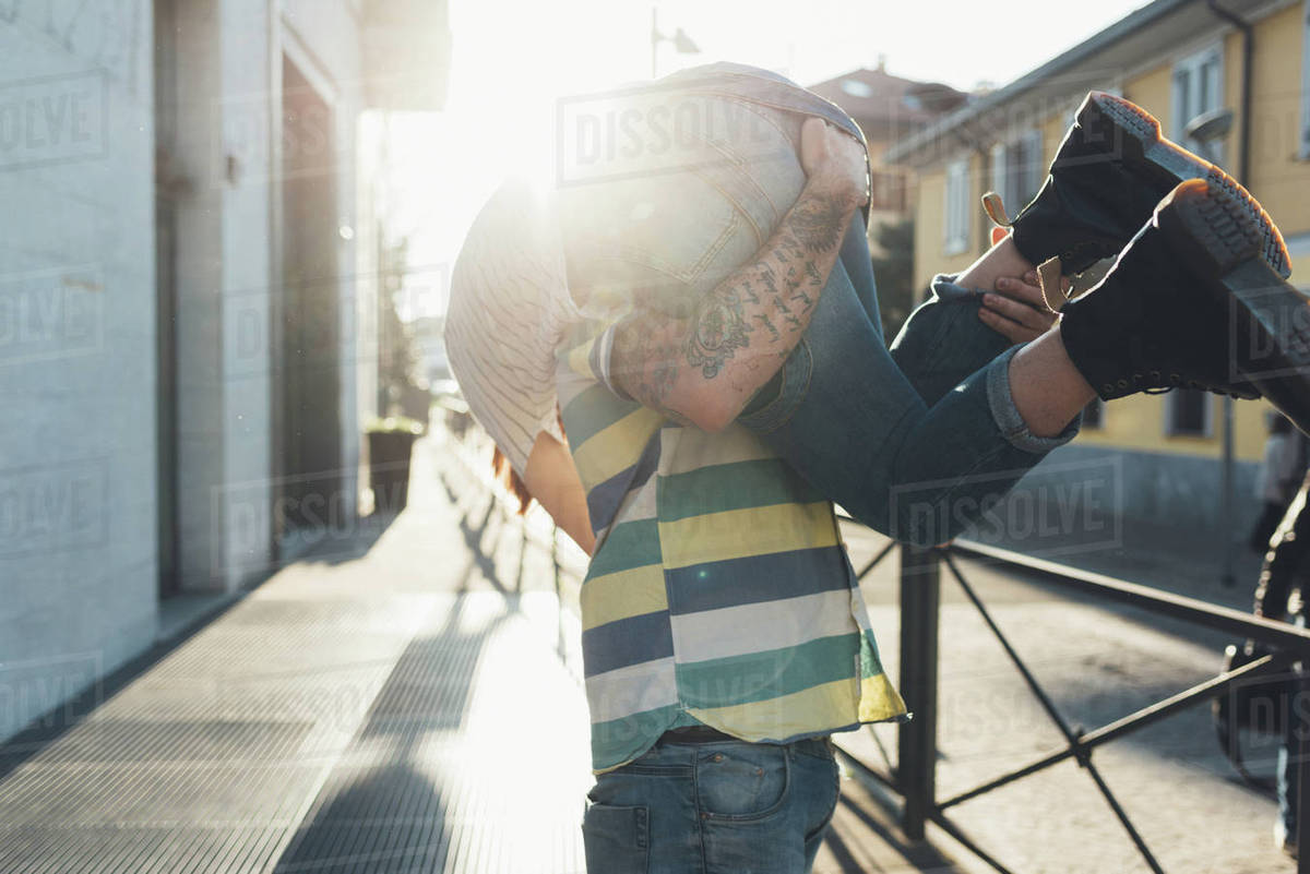 Man carrying girlfriend over his shoulder on sidewalk - Royalty-free ...