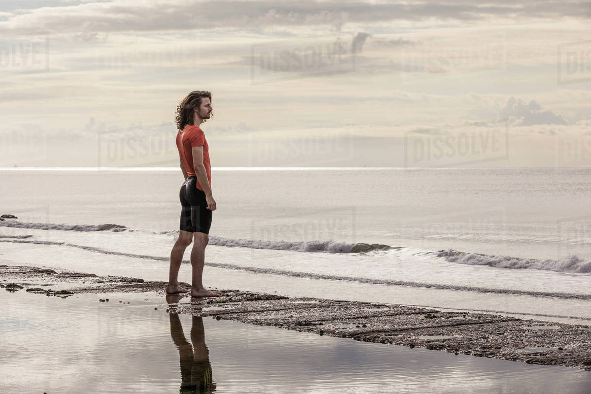 Man on shoreline looking away at view of sea - Royalty-free Stock Photo ...