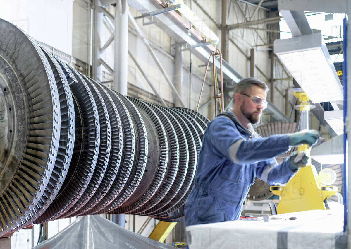 Engineer at workstation with high pressure steam turbine in turbine ...