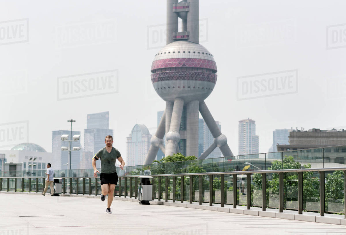 Young male runner running in Shanghai financial centre, Shanghai, China ...
