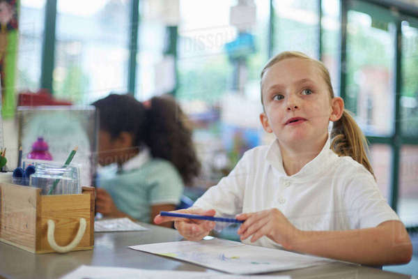 Schoolgirl looking up in classroom lesson at primary school - Royalty ...